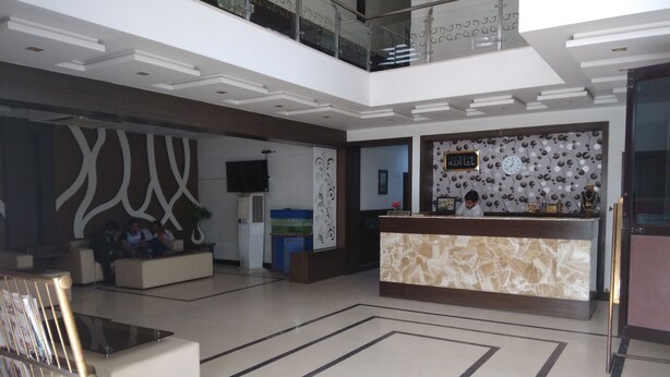 Um hall moderno com balcão de recepção, área de estar e um grande painel decorativo.