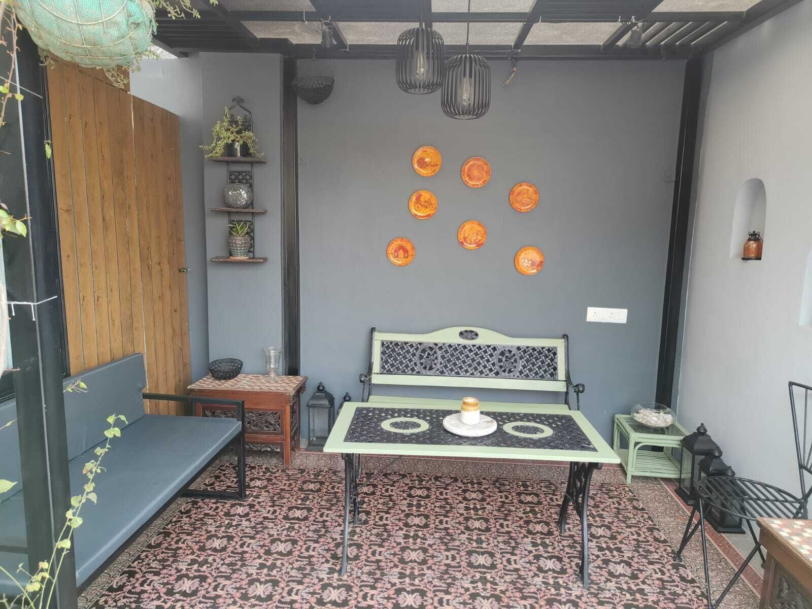 Um quarto aconchegante com um banco, uma mesa com um prato decorativo e uma parede adornada com pratos laranja redondos.