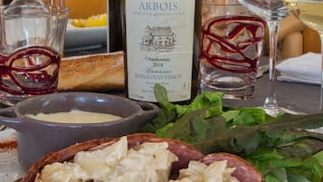 Uma mesa de jantar com uma garrafa de vinho, copos e um prato de comida.