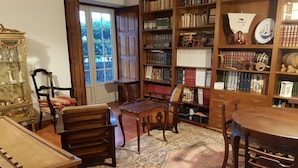 Uma biblioteca com estantes de madeira, uma janela grande e uma mesa de madeira tradicional.