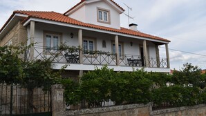 Uma casa de dois andares com varanda, paredes de pedra e telhado de telhas.