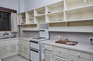 Cozinha com armários brancos, fogão e bancada com uma bandeja.