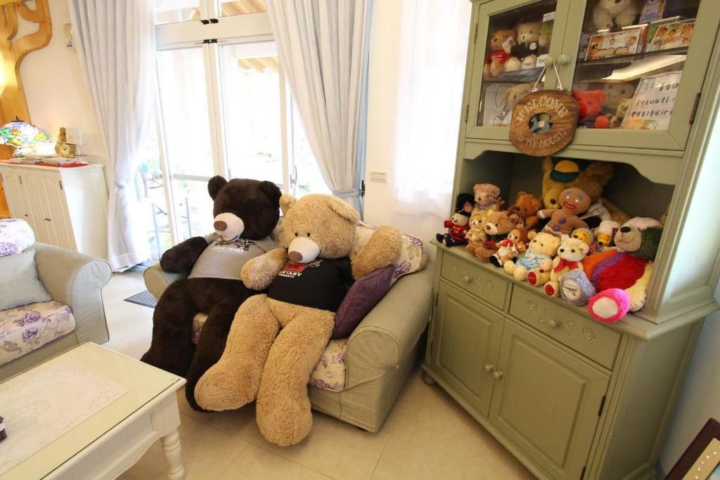 Quarto com sofá e um armário cheio de brinquedos de pelúcia.
