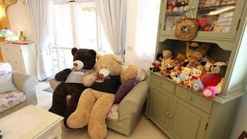 Quarto com sofá e um armário cheio de brinquedos de pelúcia.