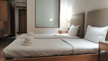 Quarto de hotel com duas camas, um espelho grande e uma mesa de cabeceira com abajur.