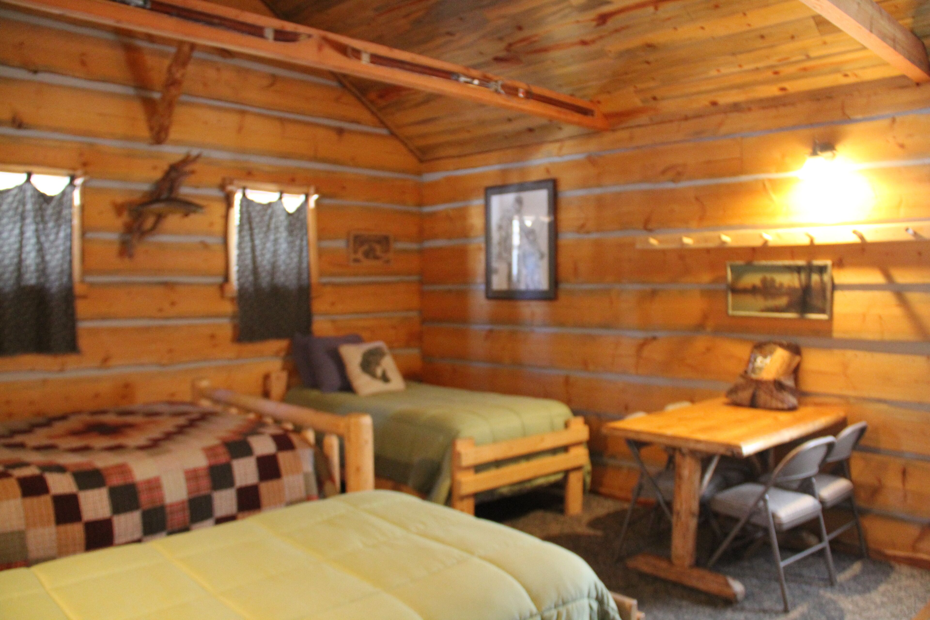 Uma cabana com duas camas, uma mesa e cadeiras.