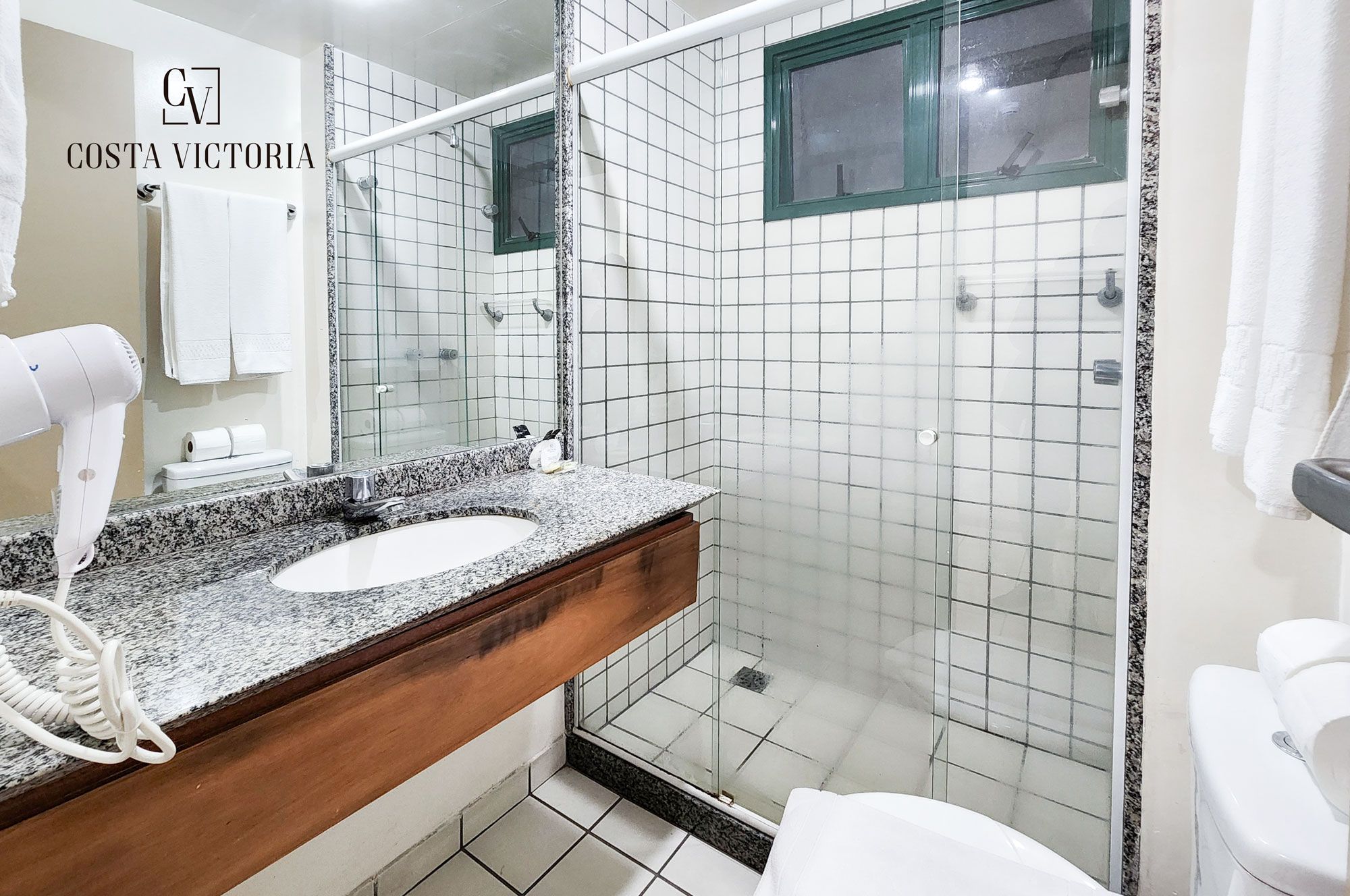 Casa de banho com lavatório branco, secador de cabelo, espelho e zona de duche.