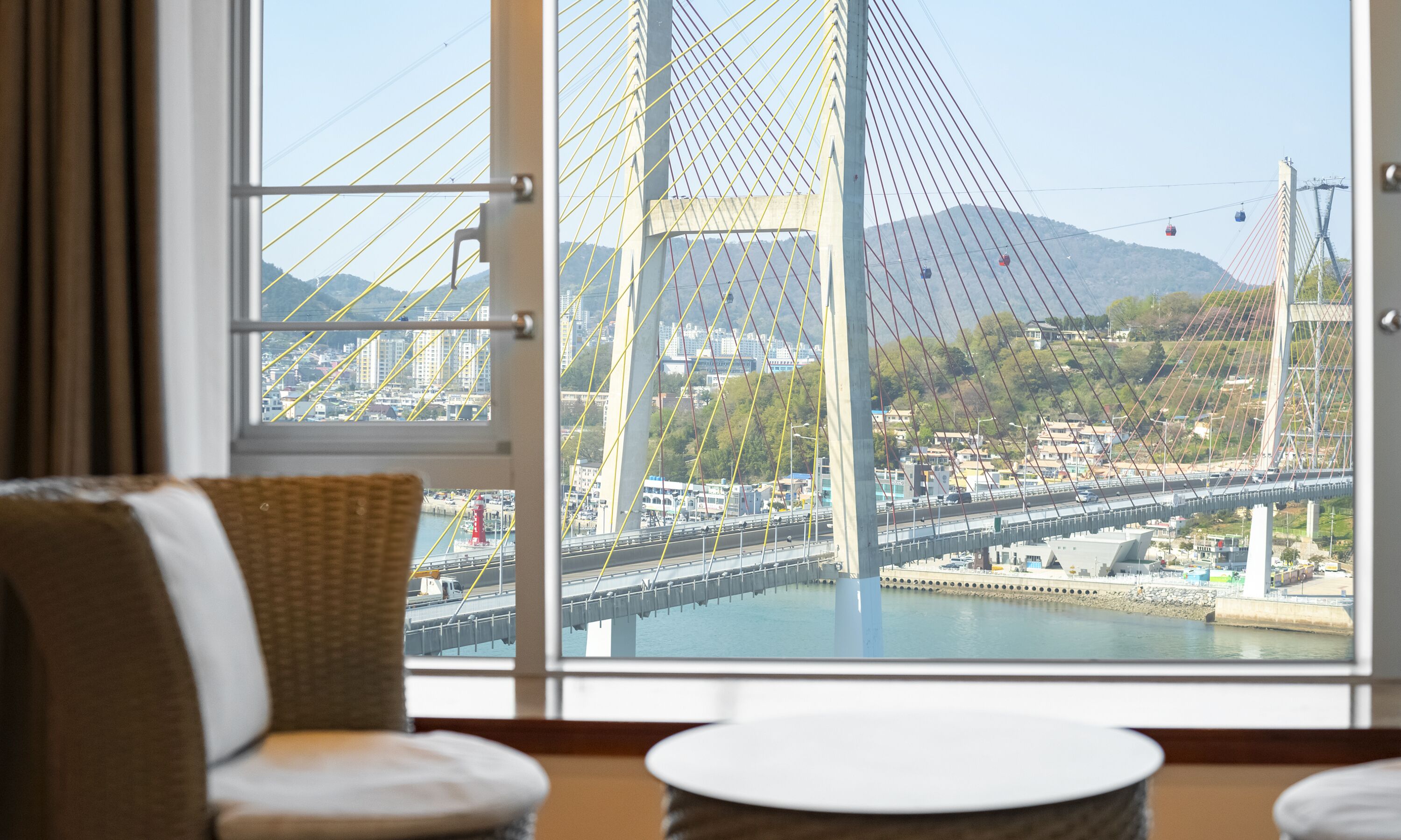 Quarto com vista para uma ponte suspensa por cabos e um corpo de água.