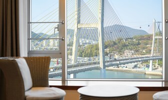 Quarto com vista para uma ponte suspensa por cabos e um corpo de água.