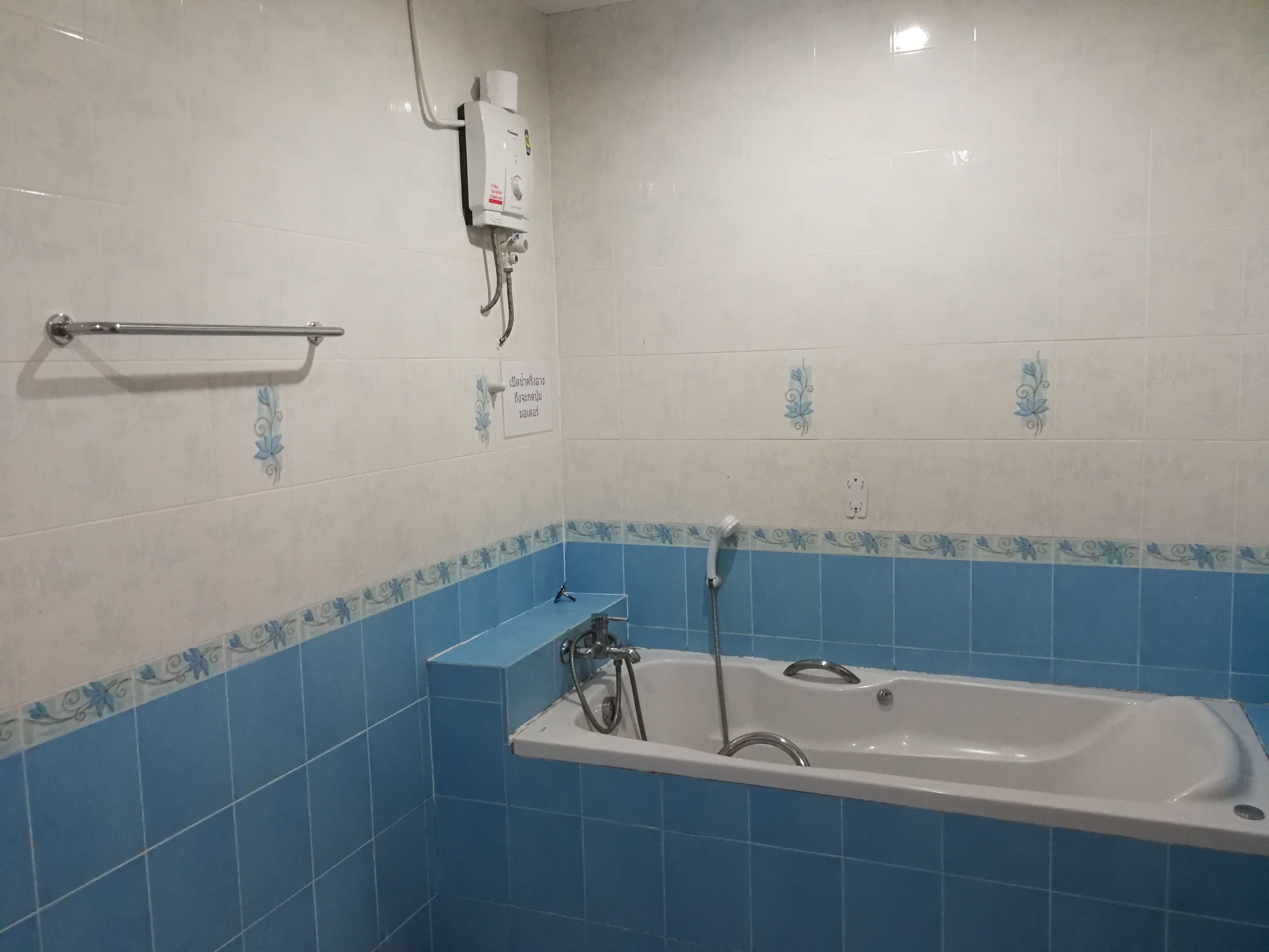 Um banheiro com banheira, porta-toalhas e rolo de papel higiênico na parede.