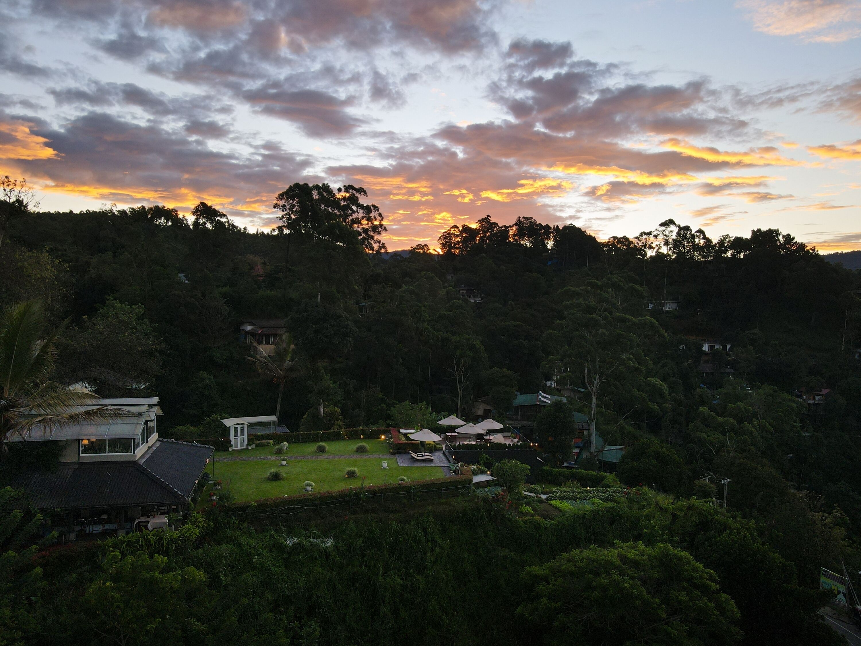 Área residencial com casas, gramado bem cuidado e vista do céu ao pôr do sol.