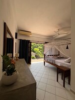 Quarto com cama, mesa de cabeceira, espelho, ventilador de teto e vista para o exterior.