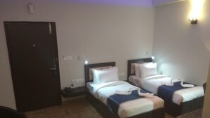 Quarto de hotel com duas camas, uma escrivaninha e uma cadeira.