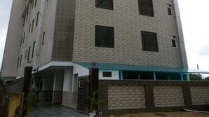 Um edifício de vários andares com design arquitetônico moderno, combinando materiais de tijolo e concreto, com várias janelas e telhado plano.