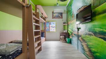 Quarto com beliches, uma escrivaninha e televisão.
