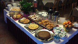 Uma mesa de buffet com diversos alimentos, incluindo tortas, doces e frutas.