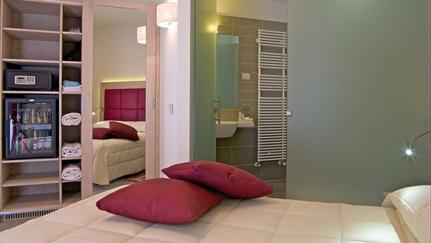 Quarto de hotel com uma cama, um guarda-roupa, casa de banho com um porta-toalhas e uma área de chuveiro.