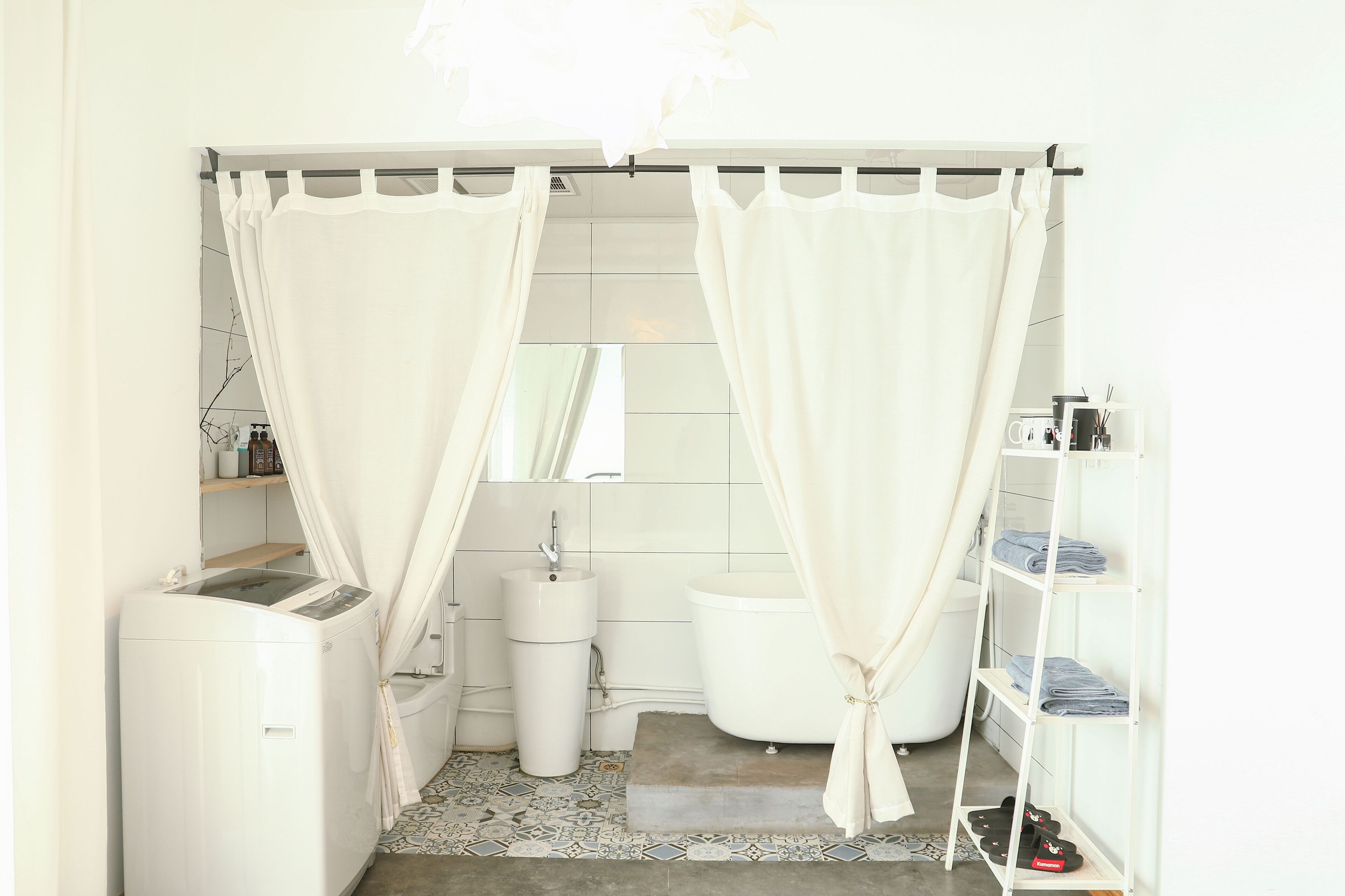 Uma casa de banho com máquina de lavar roupa, sanita e estantes com roupa dobrada.