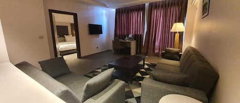 Quarto de hotel moderno com área de estar, incluindo um sofá, uma mesa de centro e uma televisão.