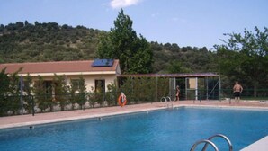 Piscina com um flutuador salva-vidas, área coberta e um edifício com painel solar.
