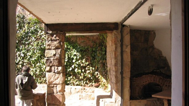 Um edifício de pedra com um banco de pedra e uma lareira.