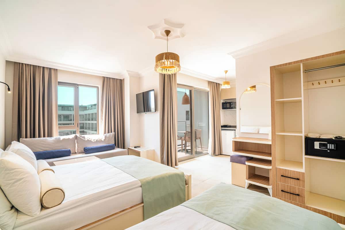 Quarto de hotel com duas camas, televisão, minibar e porta de vidro corrediça para a varanda.