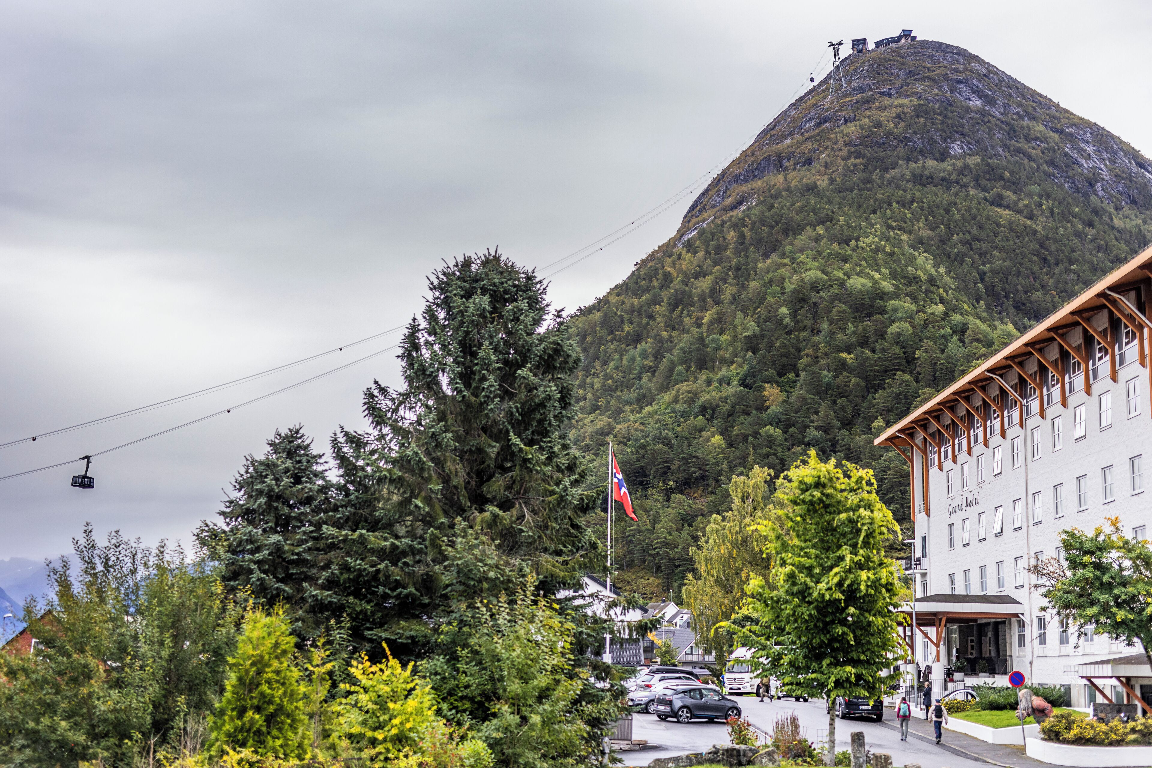 Hotel com montanhas ao fundo, uma bandeira e um teleférico.