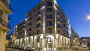 Hotel com vários andares, entrada central, varandas e estacionamento.