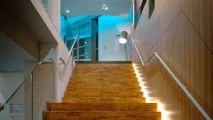Escadaria de madeira com guarda-corpos de vidro e design de interiores moderno.