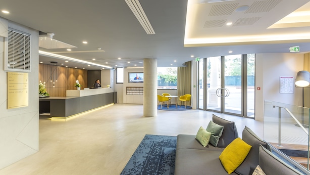 Um lobby moderno com balcão de recepção, área de estar e grandes janelas.