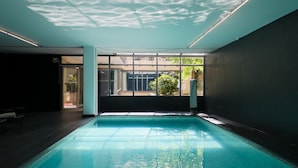 Piscina interior com paredes de vidro transparente, permitindo a entrada de luz natural.