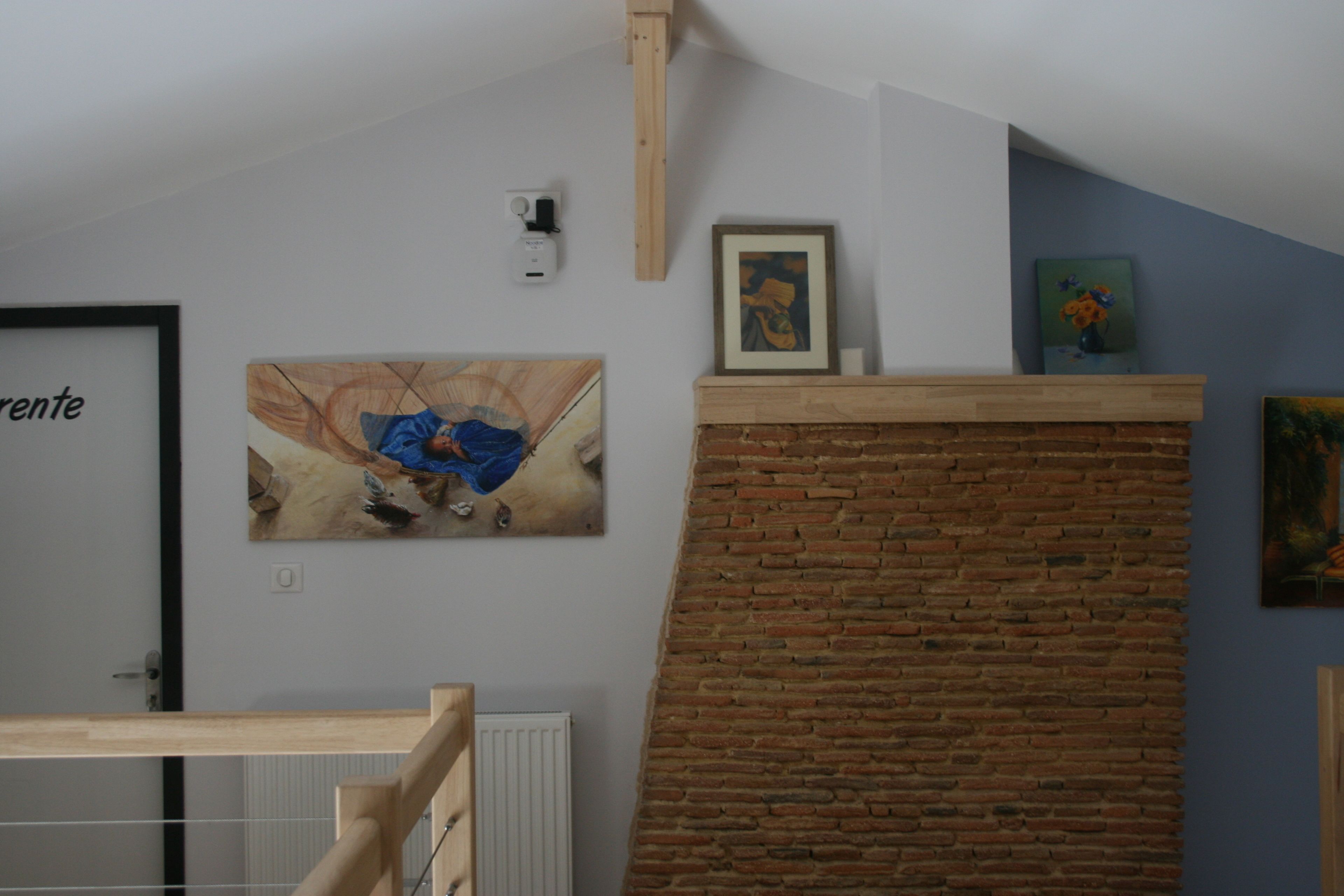 Um quarto com parede de tijolos, escada de madeira e diversas obras de arte nas paredes.