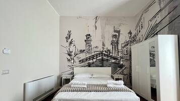 Quarto moderno com cama, mesas de cabeceira, radiador e um mural na parede com vista para a cidade.