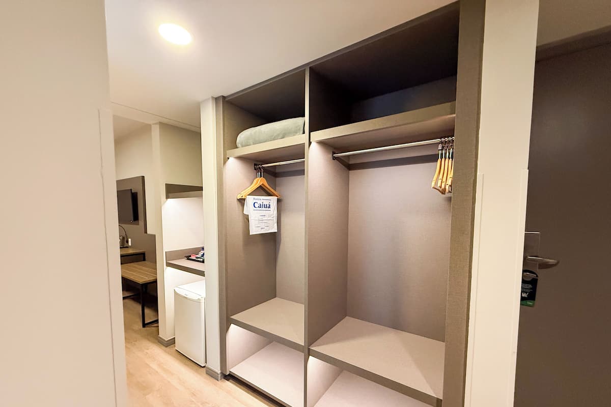 Um closet espaçoso com espaço para pendurar roupas e prateleiras, uma escrivaninha pequena com cadeira e um espelho.