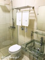Casa de banho com cabine de duche em vidro, sanita e lavatório em vidro.