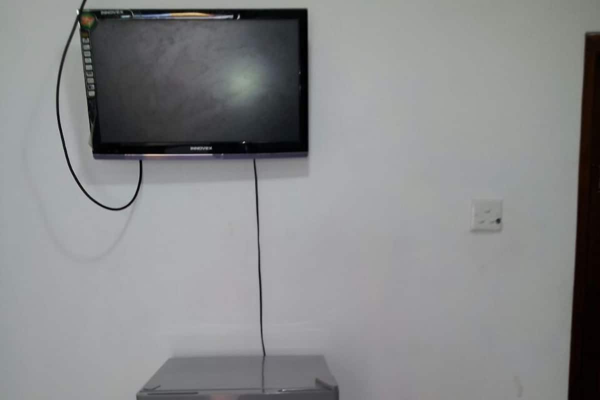 Uma televisão presa à parede acima de uma geladeira.