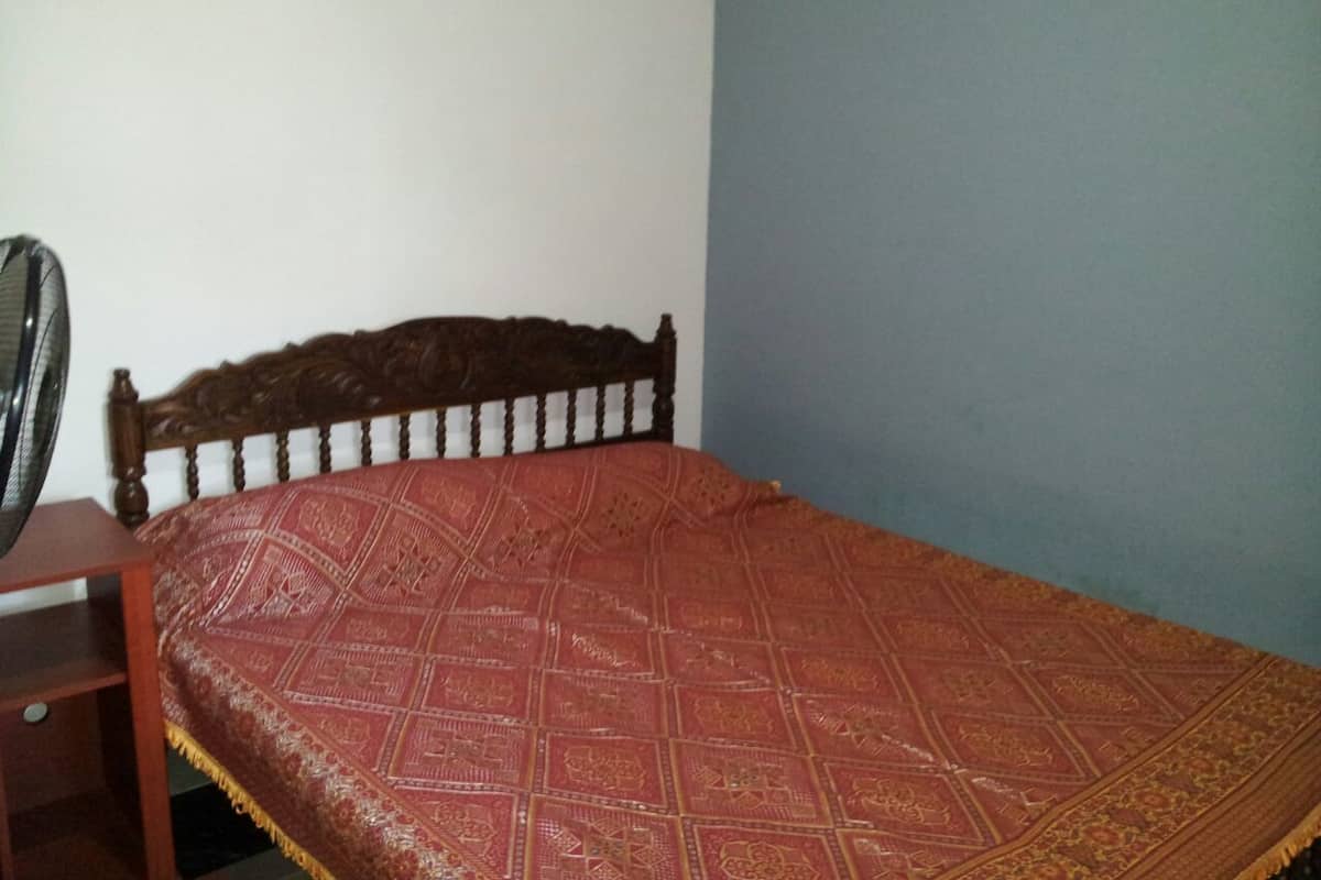 Uma cama de solteiro com colcha estampada, cabeceira de madeira e mesa de cabeceira de madeira com espelho.