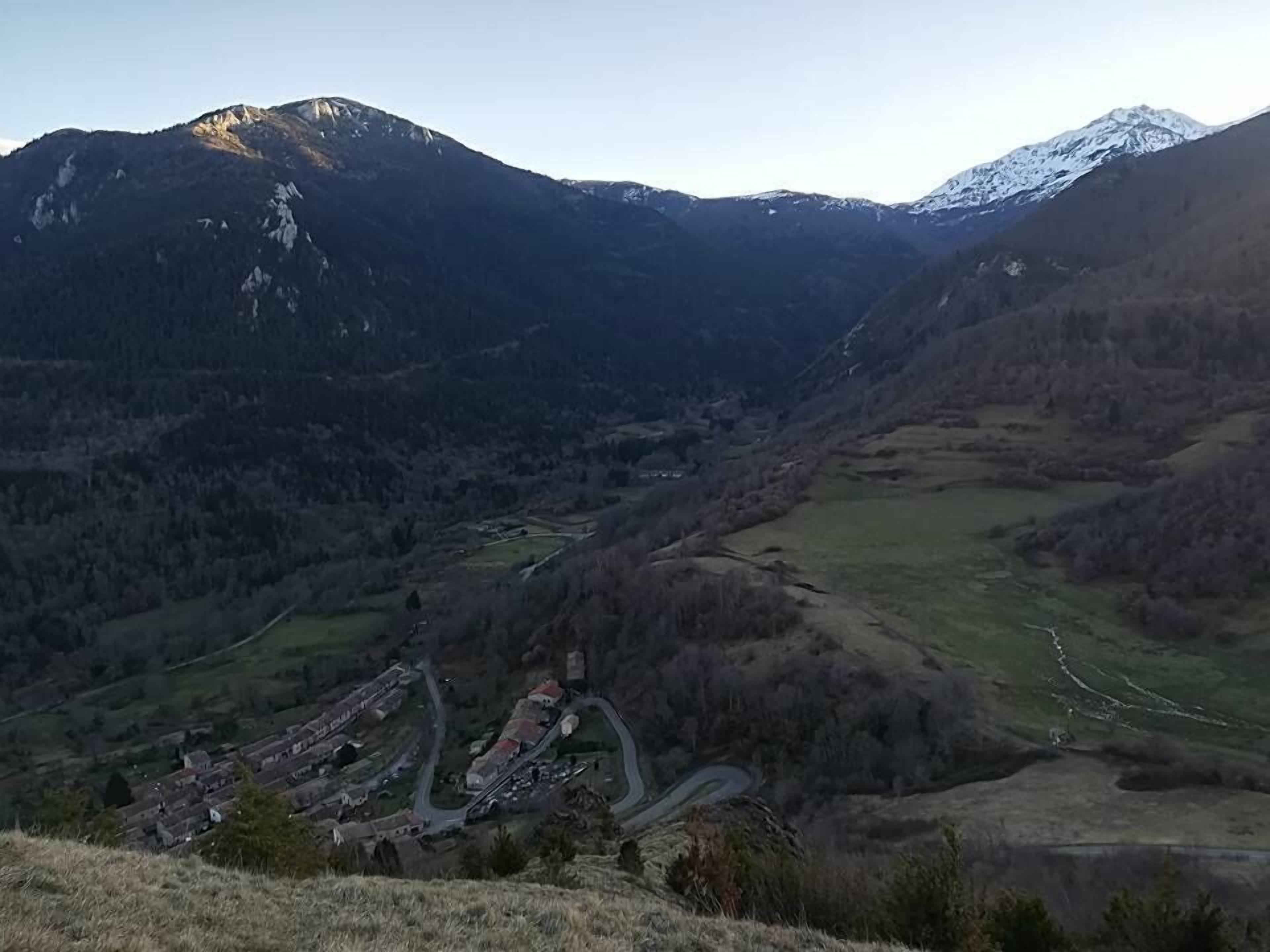 Um vale com uma estrada sinuosa e edifícios em primeiro plano.