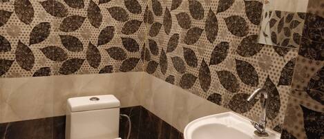Casa de banho com sanita, lavatório e azulejos com padrão.