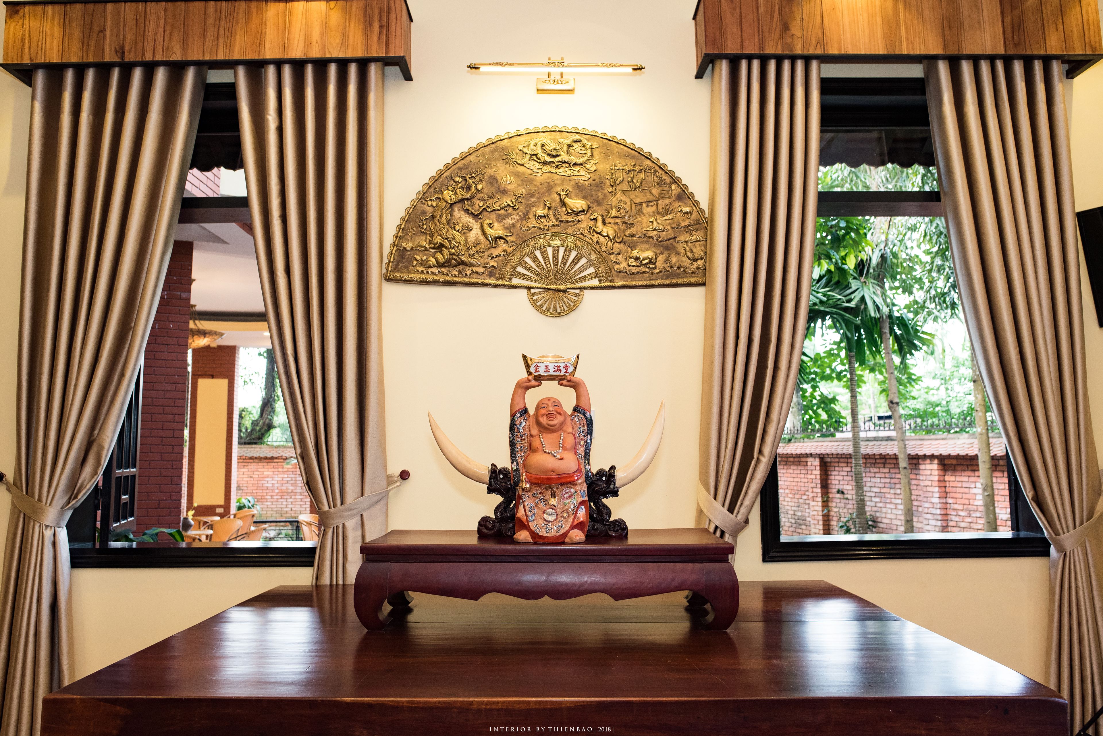 Um quarto com uma mesa de madeira, uma estátua e um ornamento pendurado na parede.
