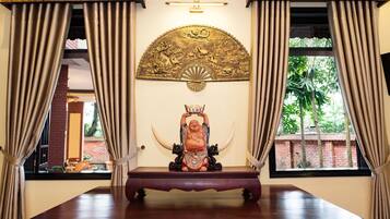 Um quarto com uma mesa de madeira, uma estátua e um ornamento pendurado na parede.