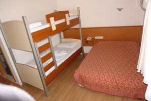 Uma cama beliche com cabeceira de madeira e uma cama inferior com colcha estampada vermelha.