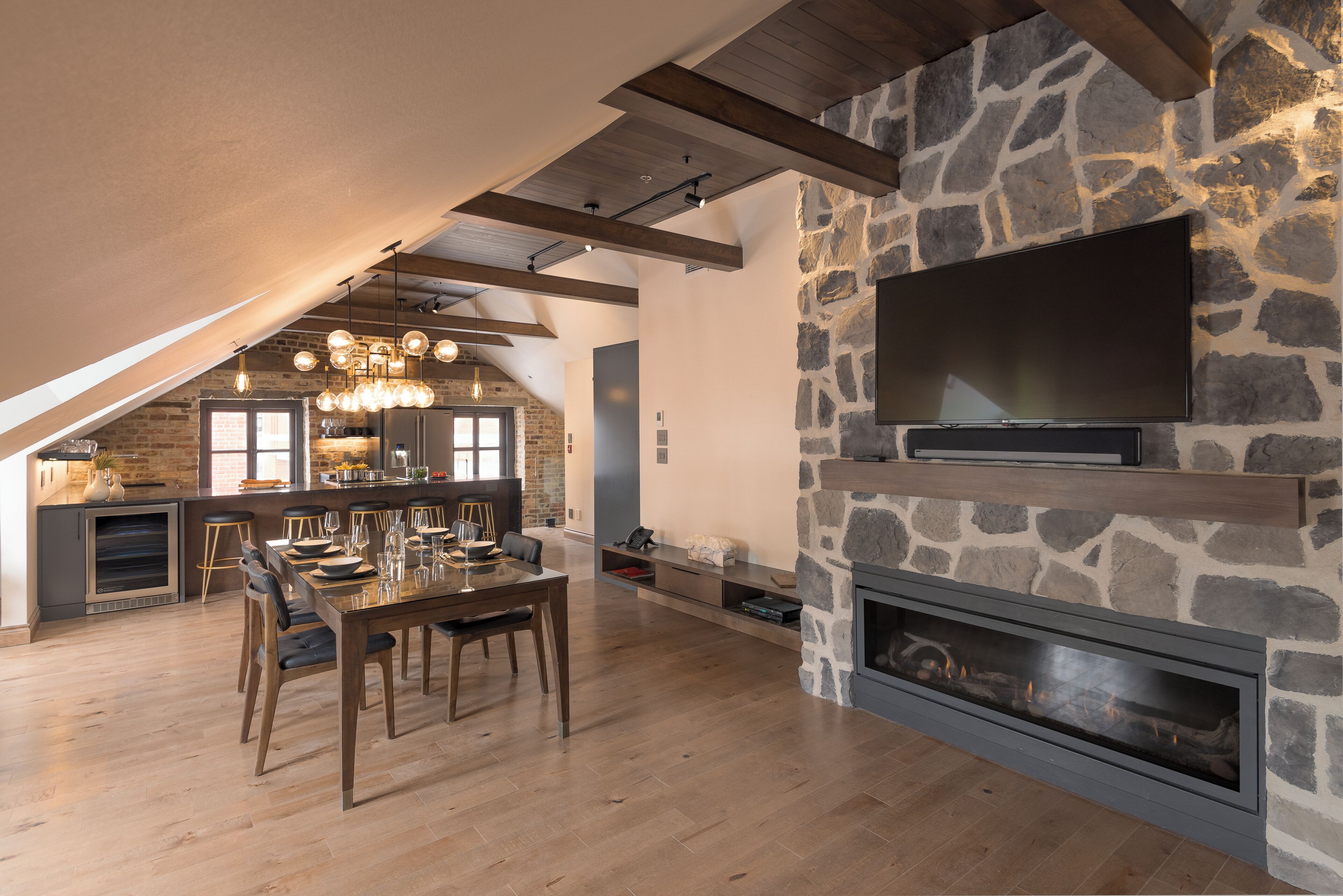Um loft amplo com área de refeições, cozinha e lareira de pedra.