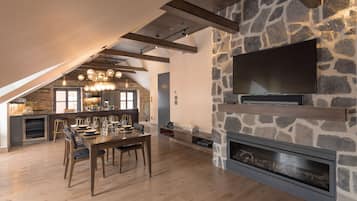Um loft amplo com área de refeições, cozinha e lareira de pedra.