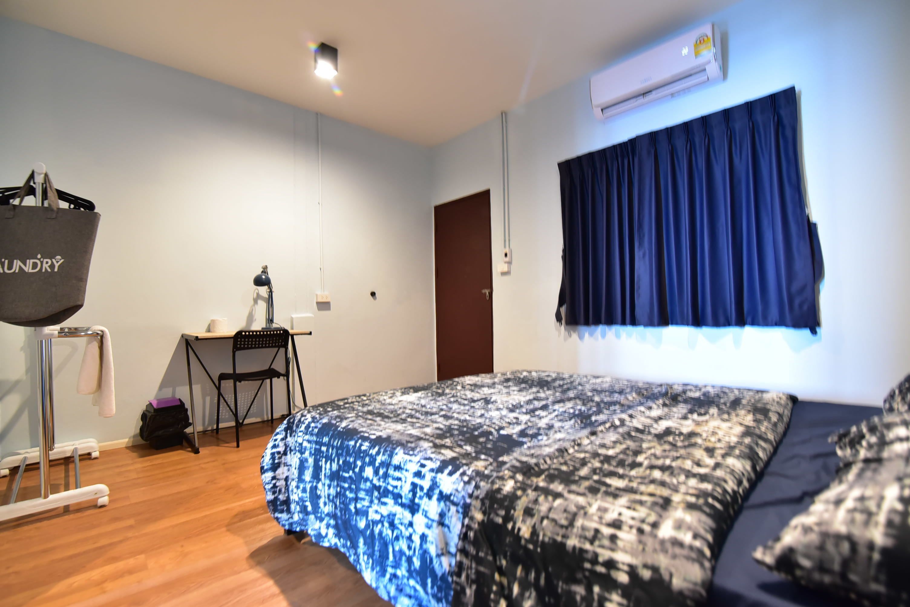 Quarto com cama, escrivaninha, cadeira e cesto de roupa.