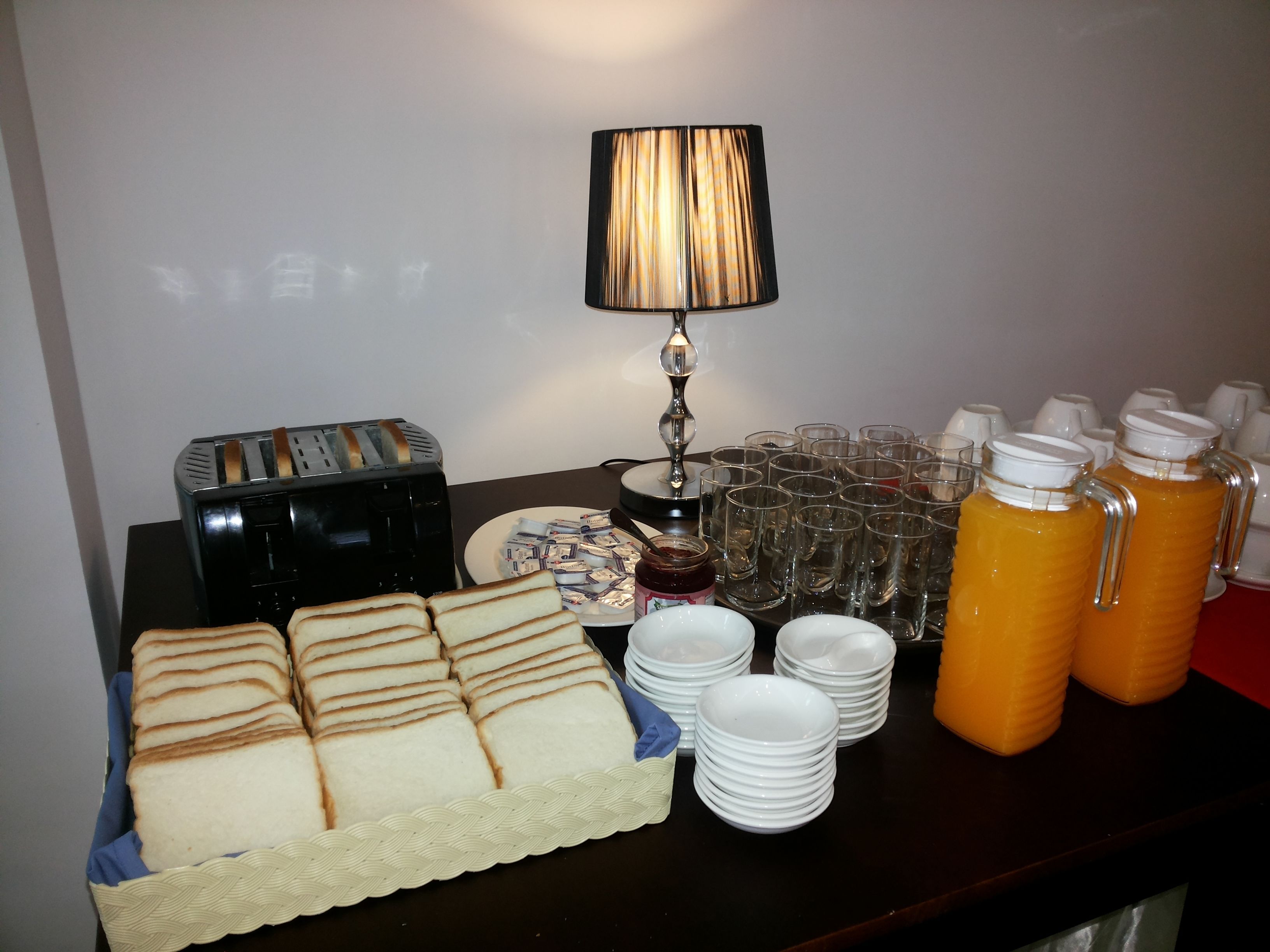 Mesa de buffet de café da manhã com pães, geleias, copos e recipientes de suco.