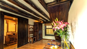 Interior em madeira com um vaso de flores sobre uma mesa, mobiliário de madeira e uma janela.