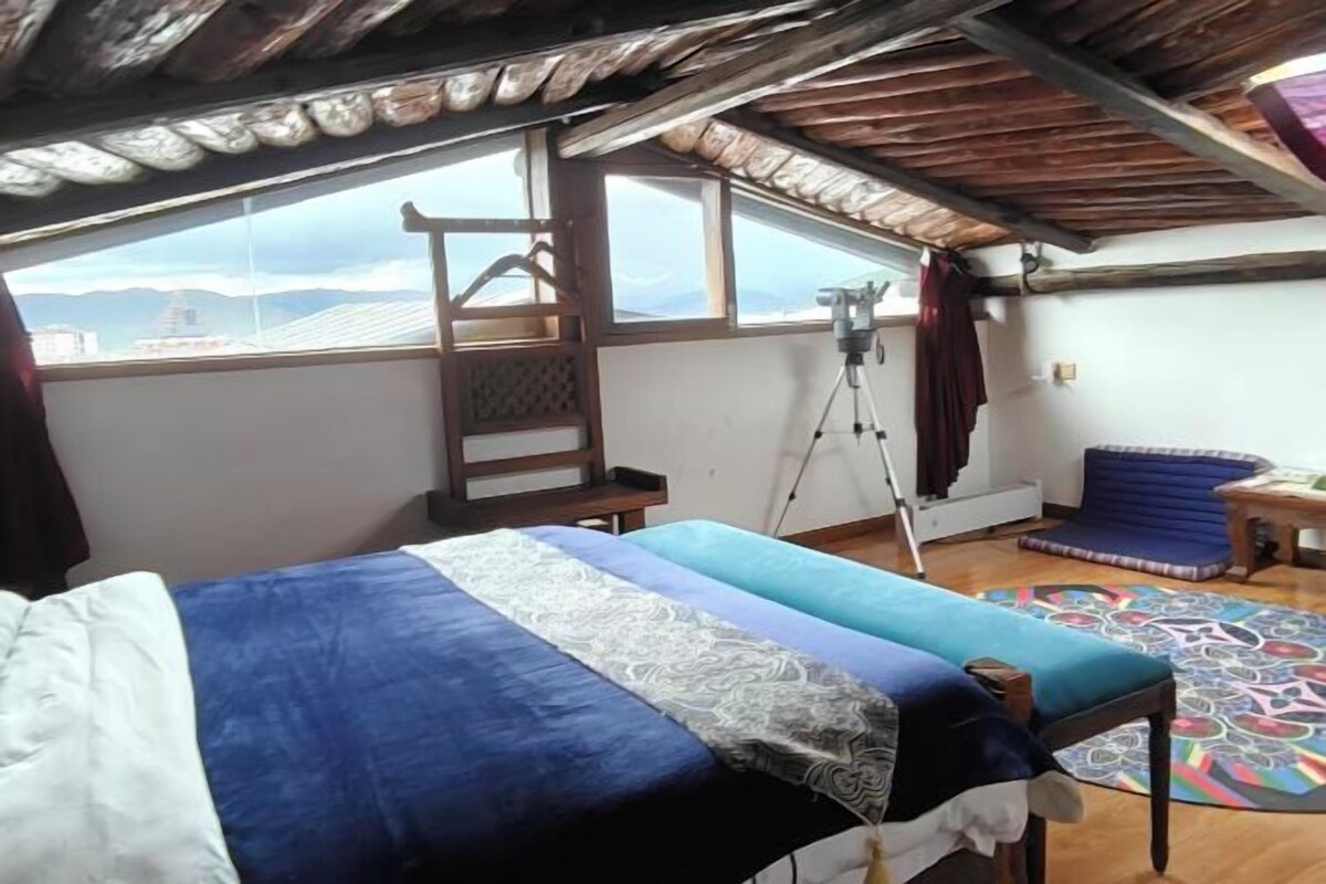 Quarto com cama, um tripé e vista para as montanhas.