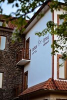 Um edifício com fachada de pedra e uma parede branca com o texto "Mirav Hotel".