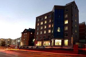 Um hotel de vários andares com design moderno, apresentando uma combinação de fachadas em tijolo e vidro.